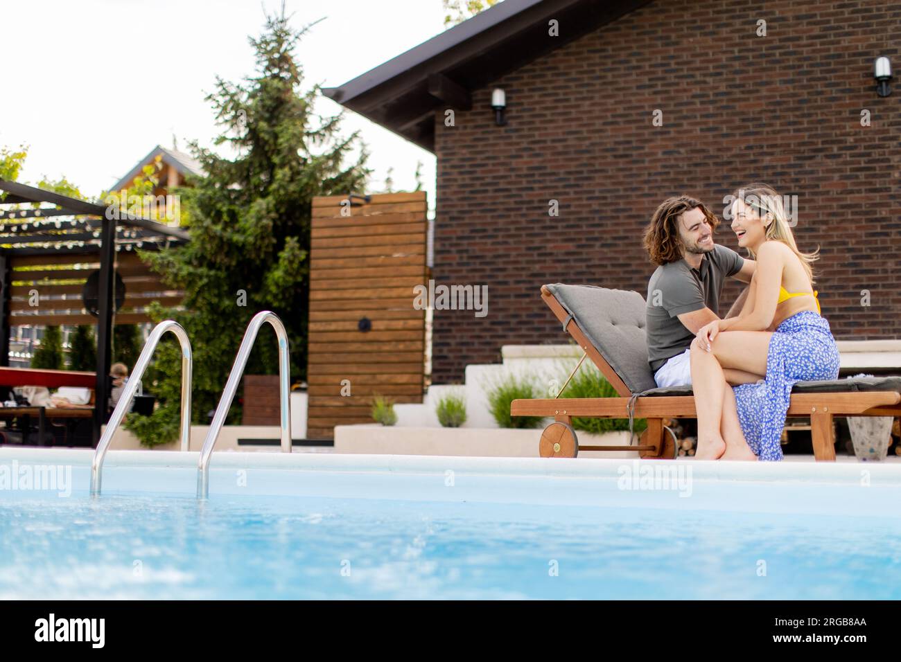 Handsome young couple relaxing by the swimming pool in the house backyard Stock Photo - Alamy
