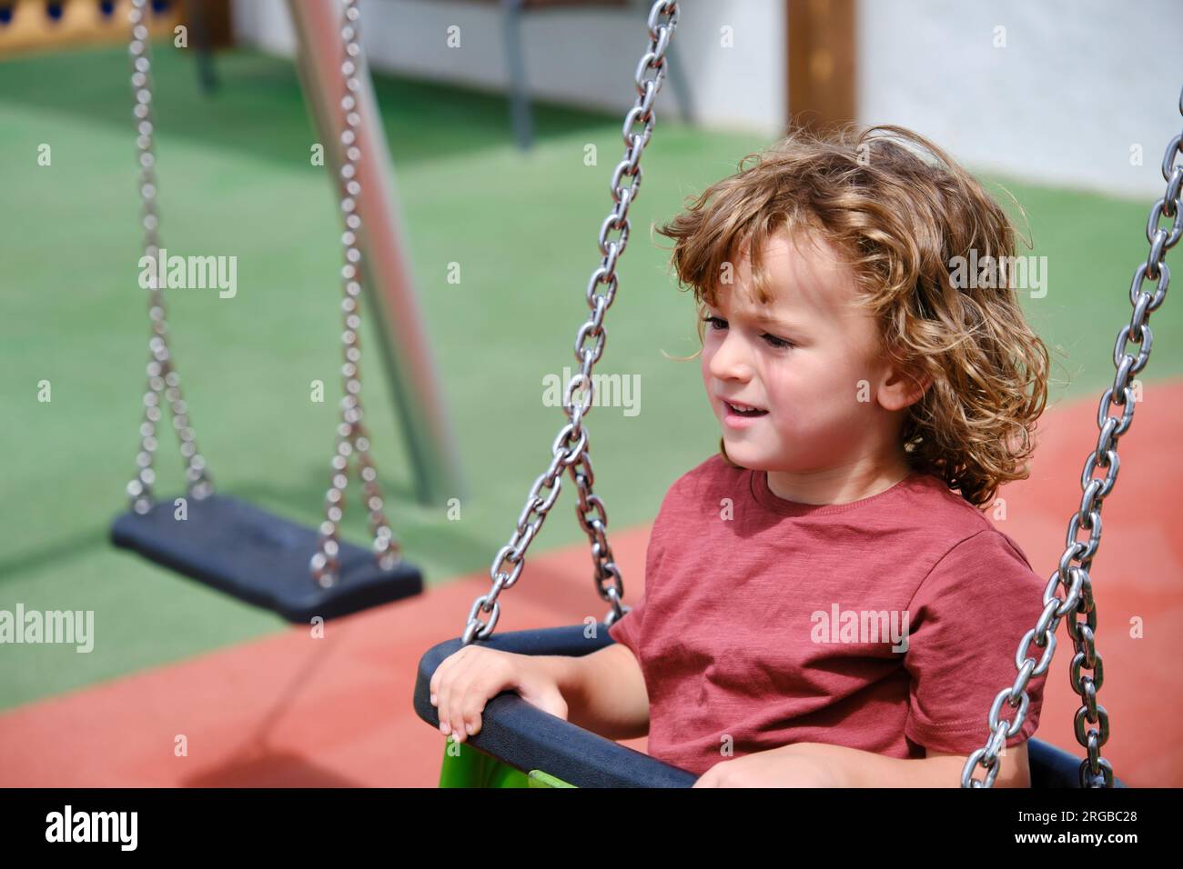 Child swinging on play area in sunshine Stock Photo - Alamy