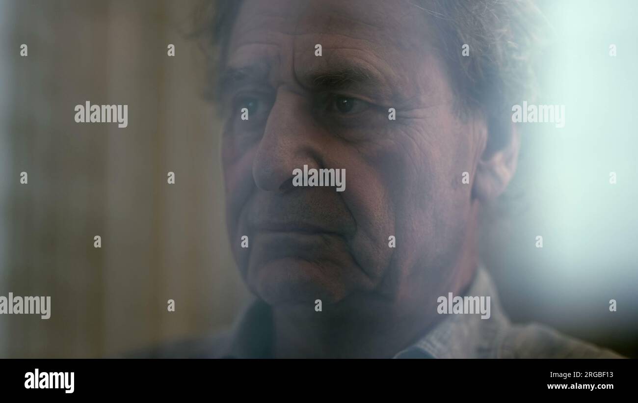 One serious older man seen thinking about life, seen through window ...