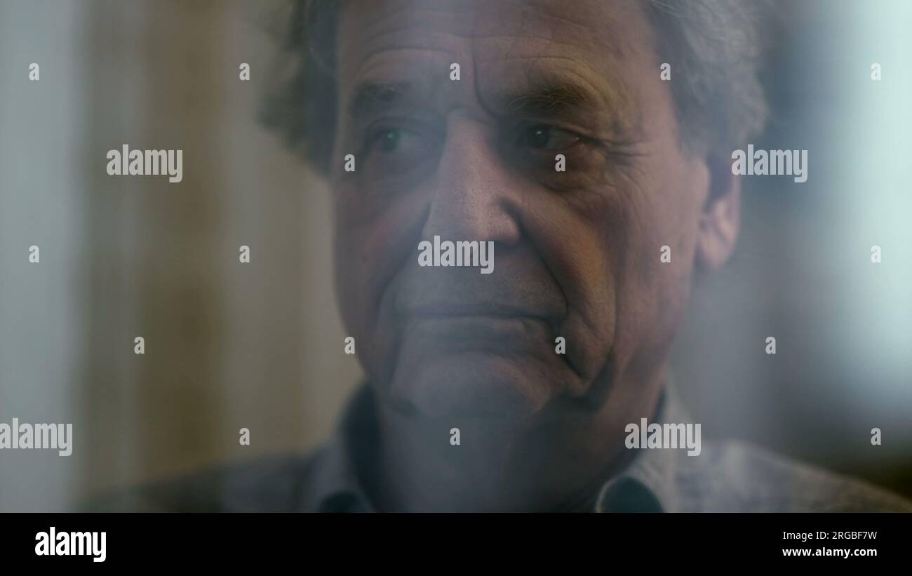One serious older man seen thinking about life, seen through window ...
