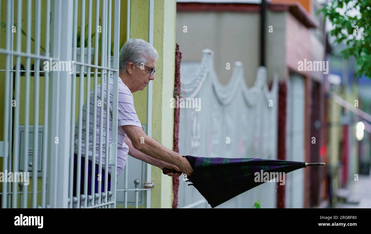Person arriving home during rainy day, opening gate and closes umbrella ...
