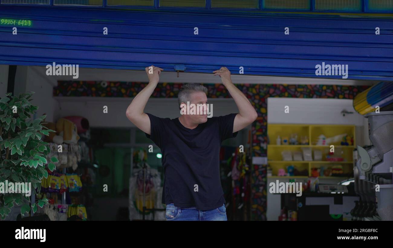 Owner of local Petshop on sidewalk closing garage storefront Stock Photo - Alamy