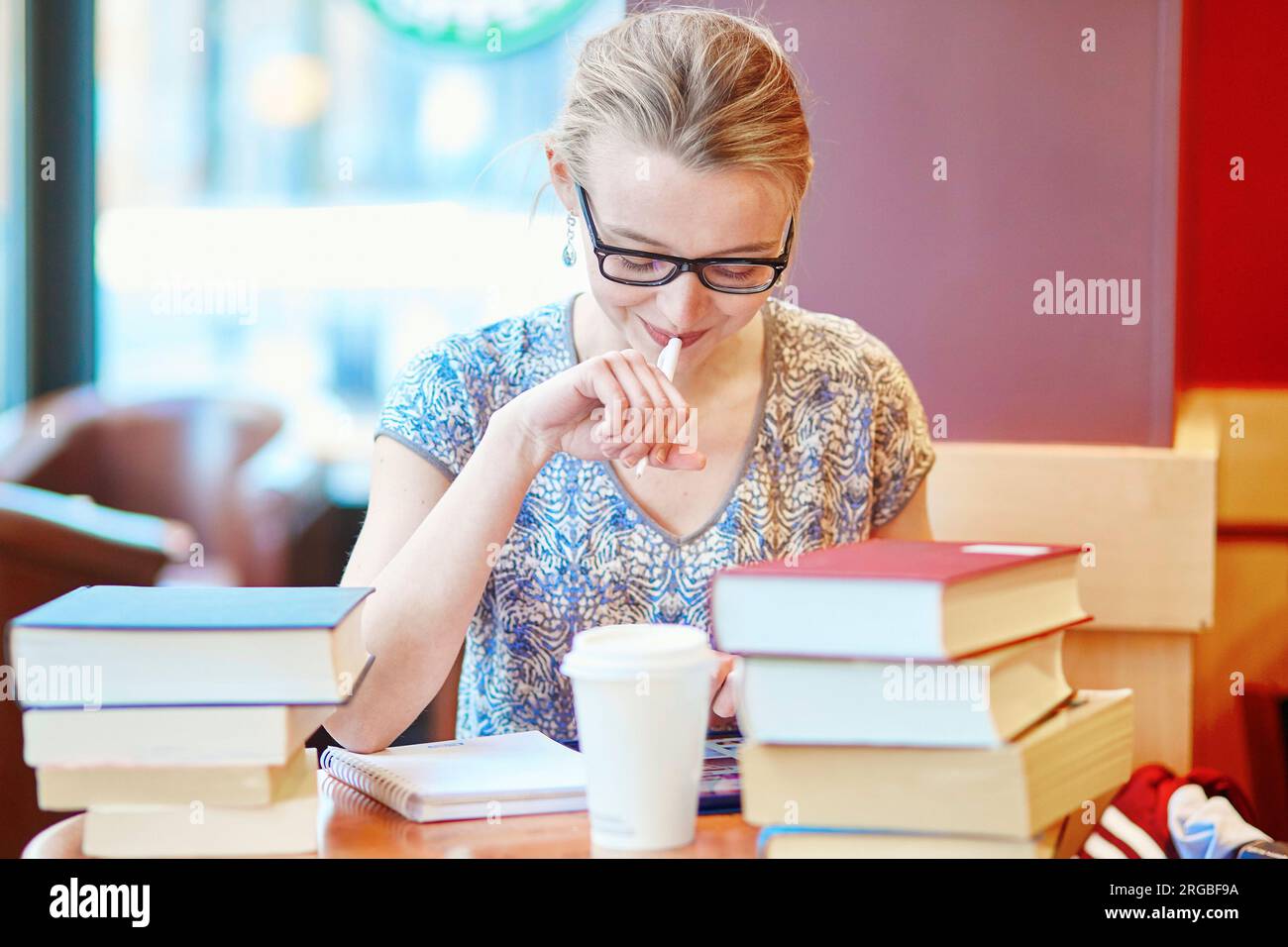 Beautiful young student with lots of books, studying or preparing for ...
