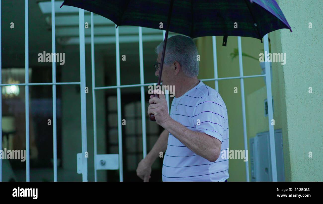 Senior Man Opens Gate, Steps out from Home with Umbrella in the Rain ...