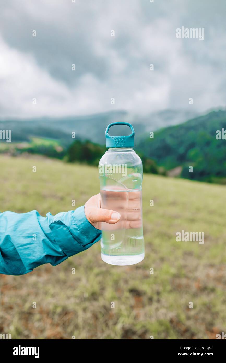 caucasian 50s blonde girl drinking water from plastic bottle. Mountain ...