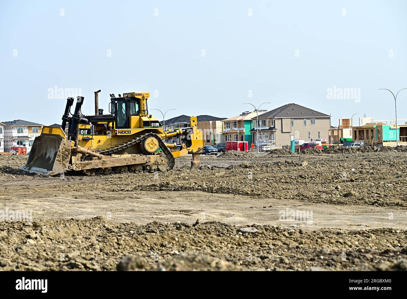 Residential construction site with a large dozer in the foreground, and ...