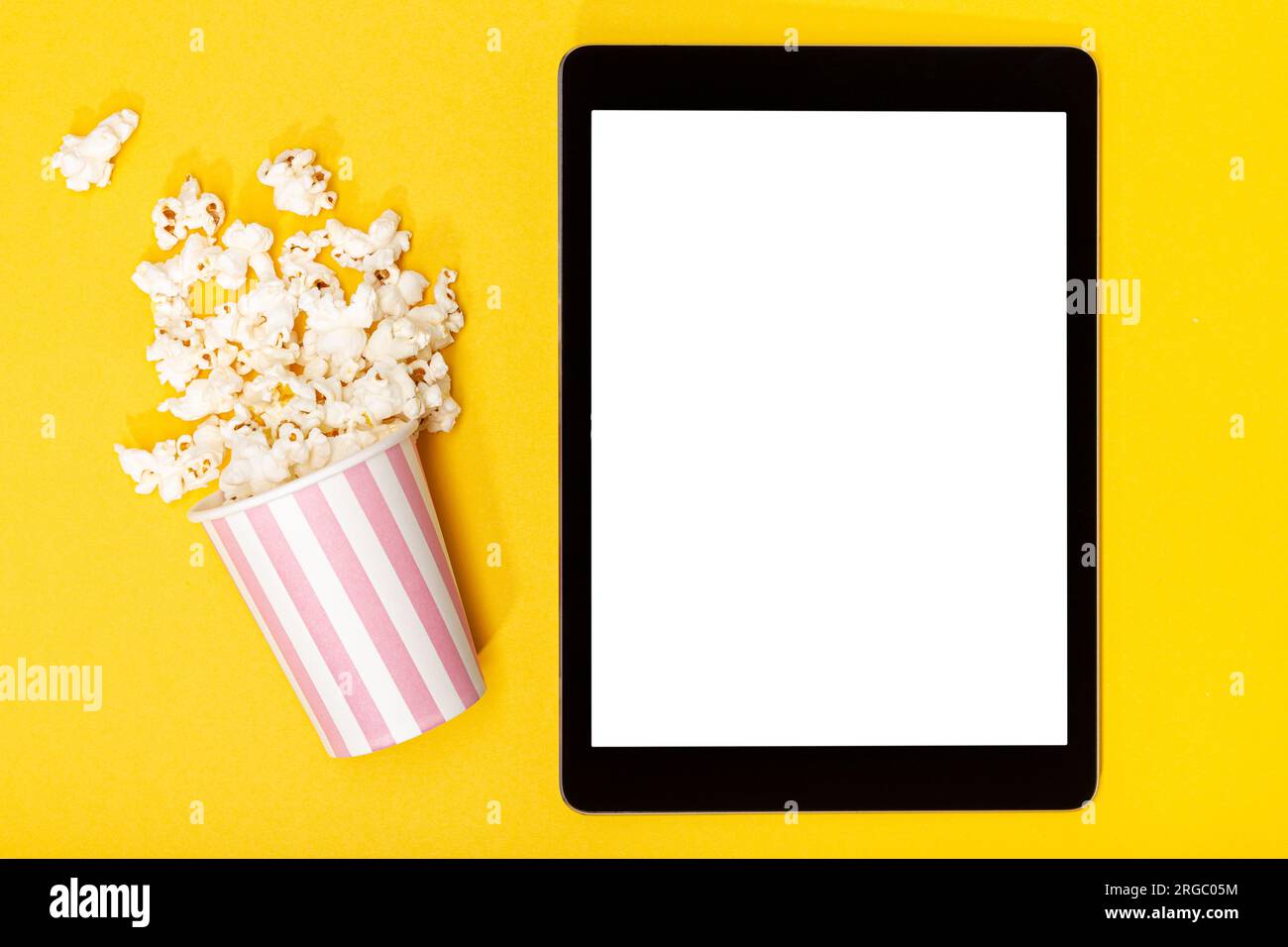Blank white screen tablet and popcorn bucket on yellow background ...