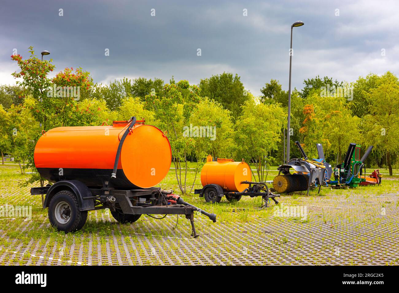 orange barrel trailer stands in the parking lot. street watering tank ...