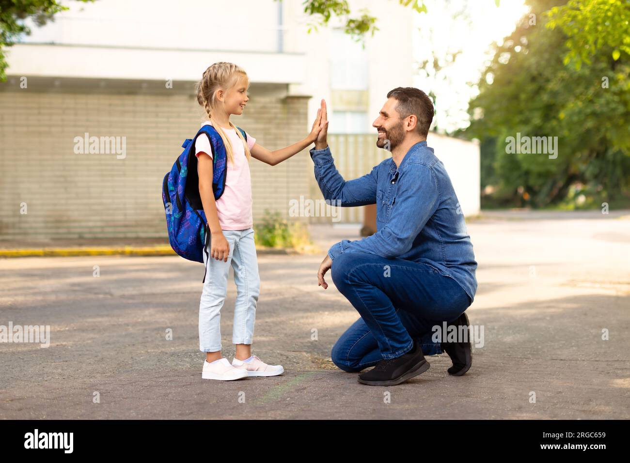 Back to school. Father giving high five to daughter, meeting after ...