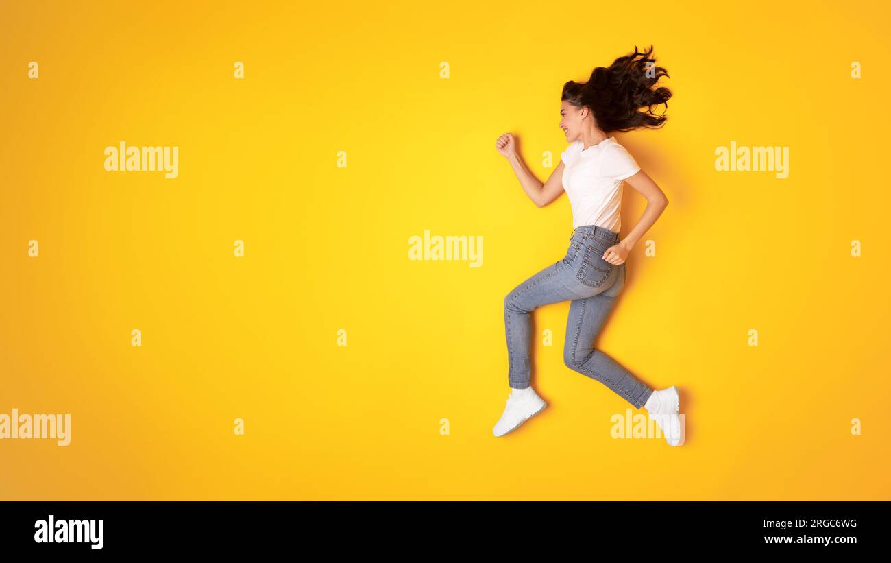 Happy Lady Running In Mid Air Looking Aside, Yellow Background Stock ...