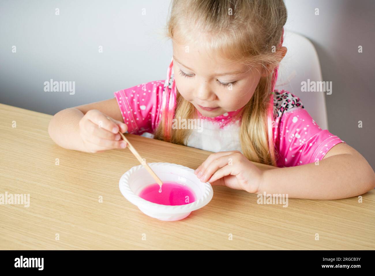 Cute Caucasian girl is making slime from scratch. Children education ...