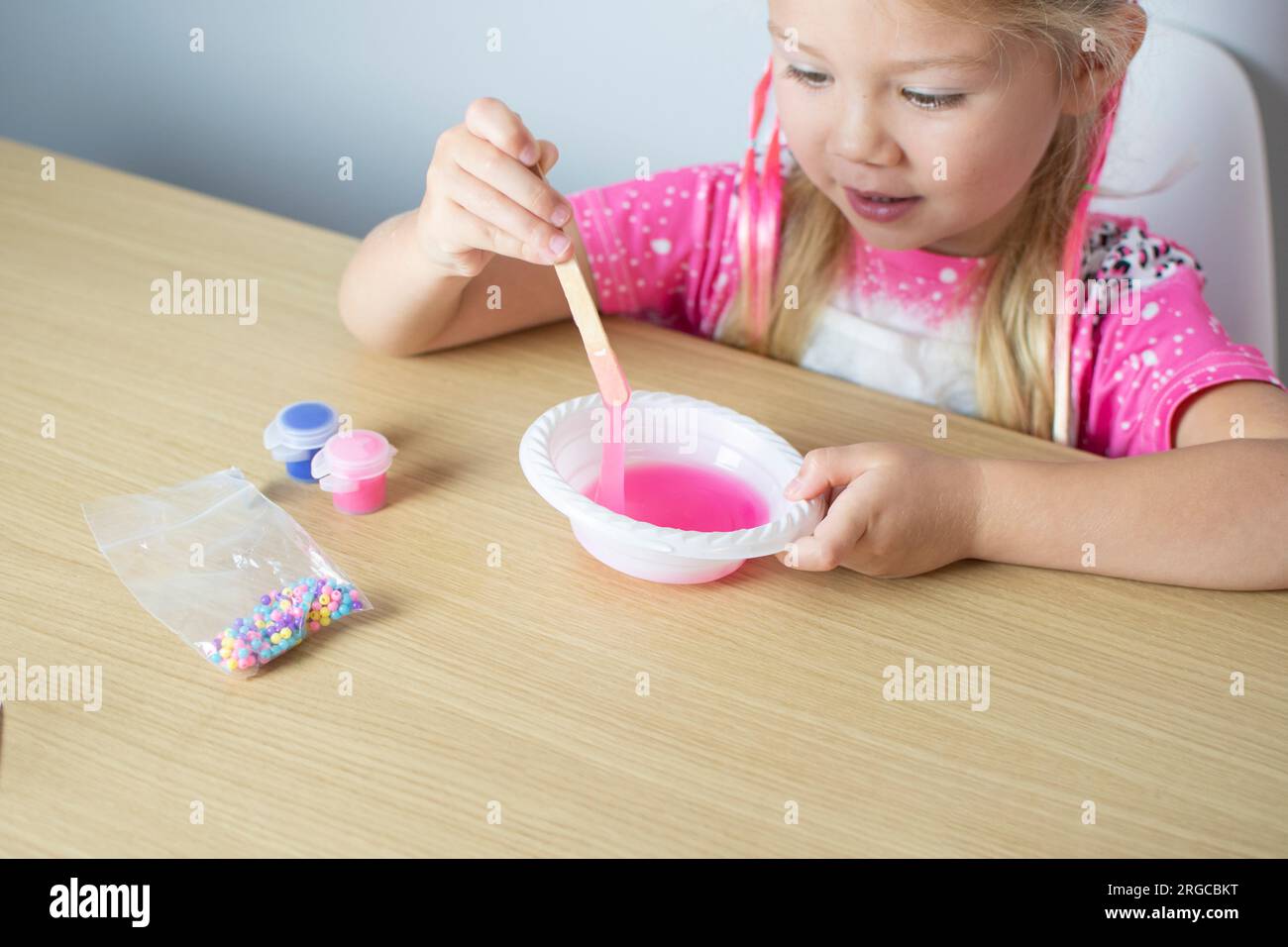 Cute Caucasian girl is making slime from scratch. Children education ...