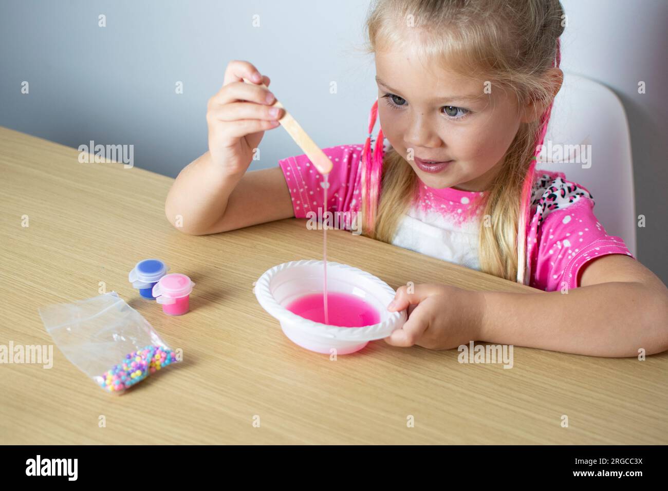 Cute Caucasian girl is making slime from scratch. Children education ...