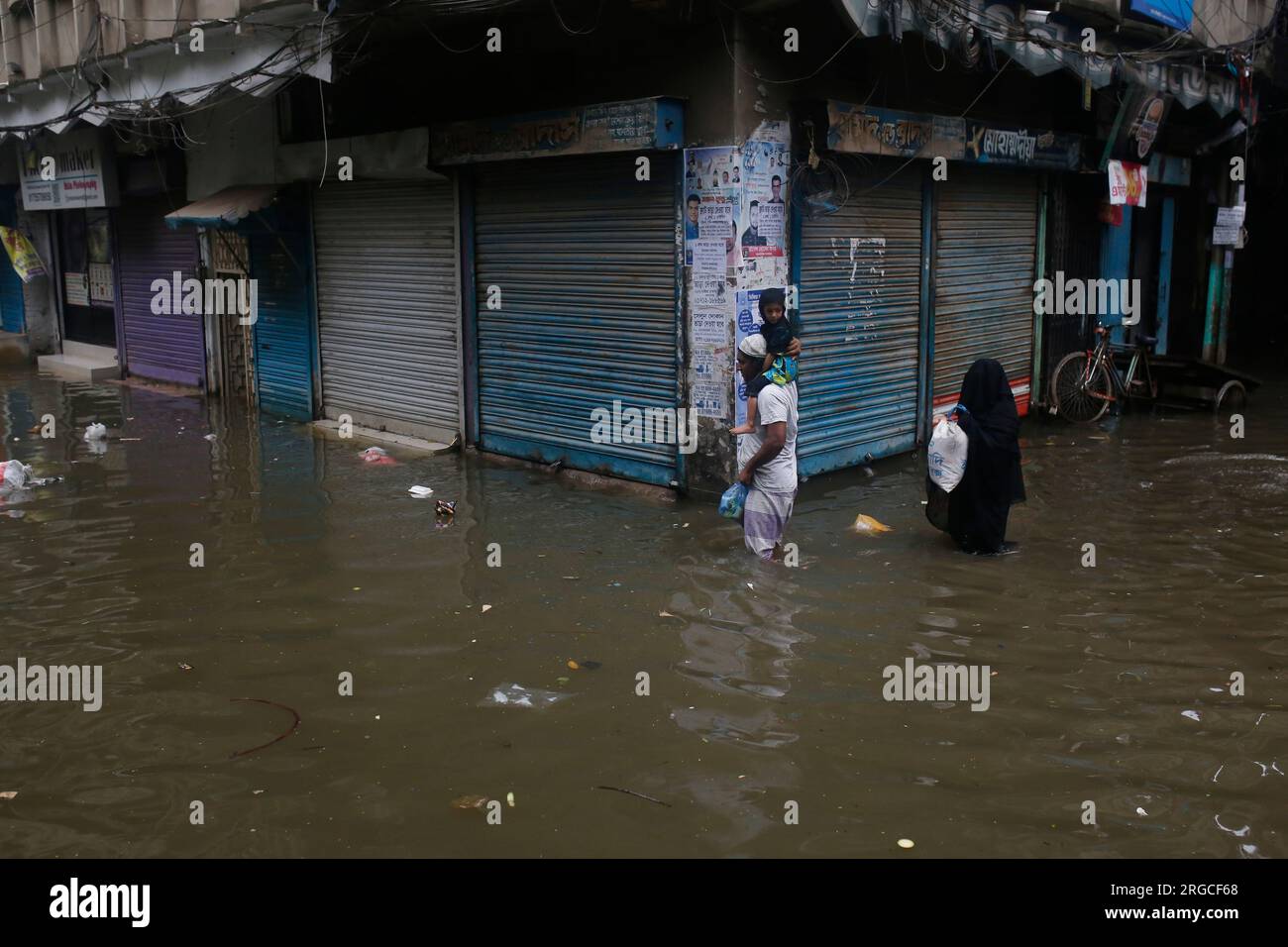 DHAKA, BANGLADESH- AUGUST 7, 2023: Residents walk through flooded street after heavy rainfall in ...