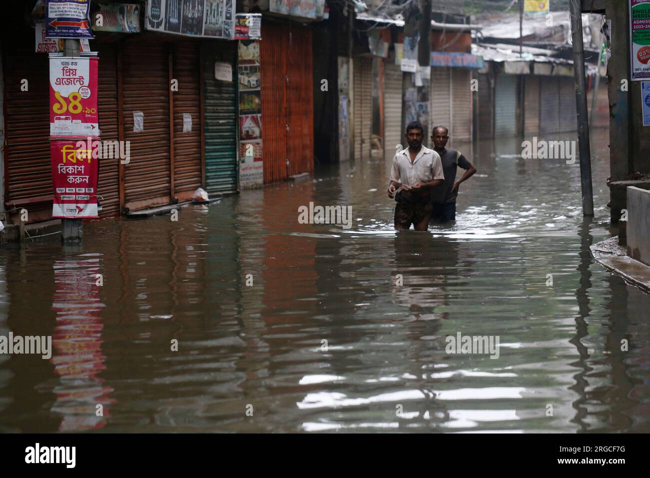 DHAKA, BANGLADESH- AUGUST 7, 2023: Residents walk through flooded street after heavy rainfall in ...