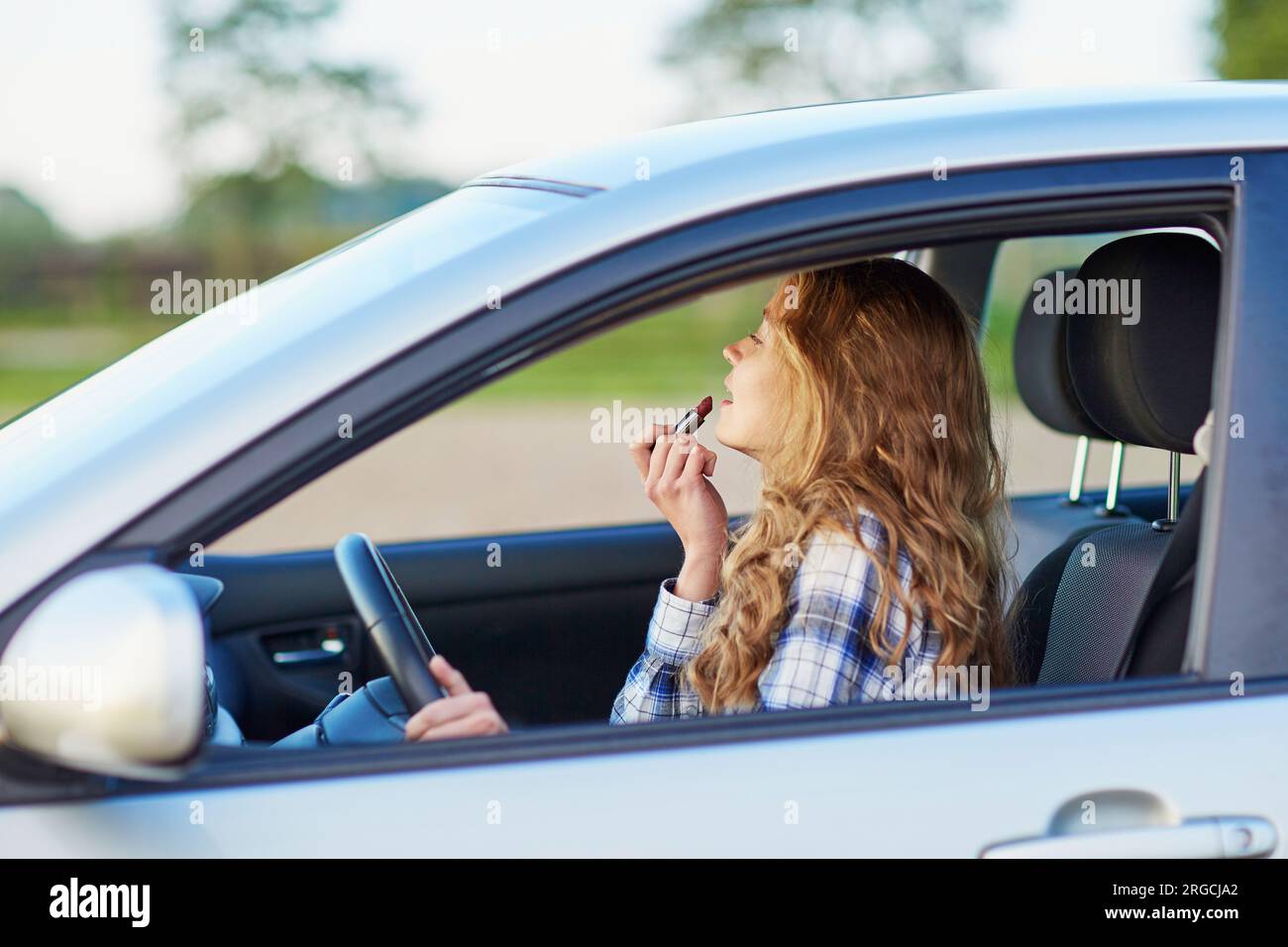 Beautiful blond woman applying lipstick in a car while driving Stock ...