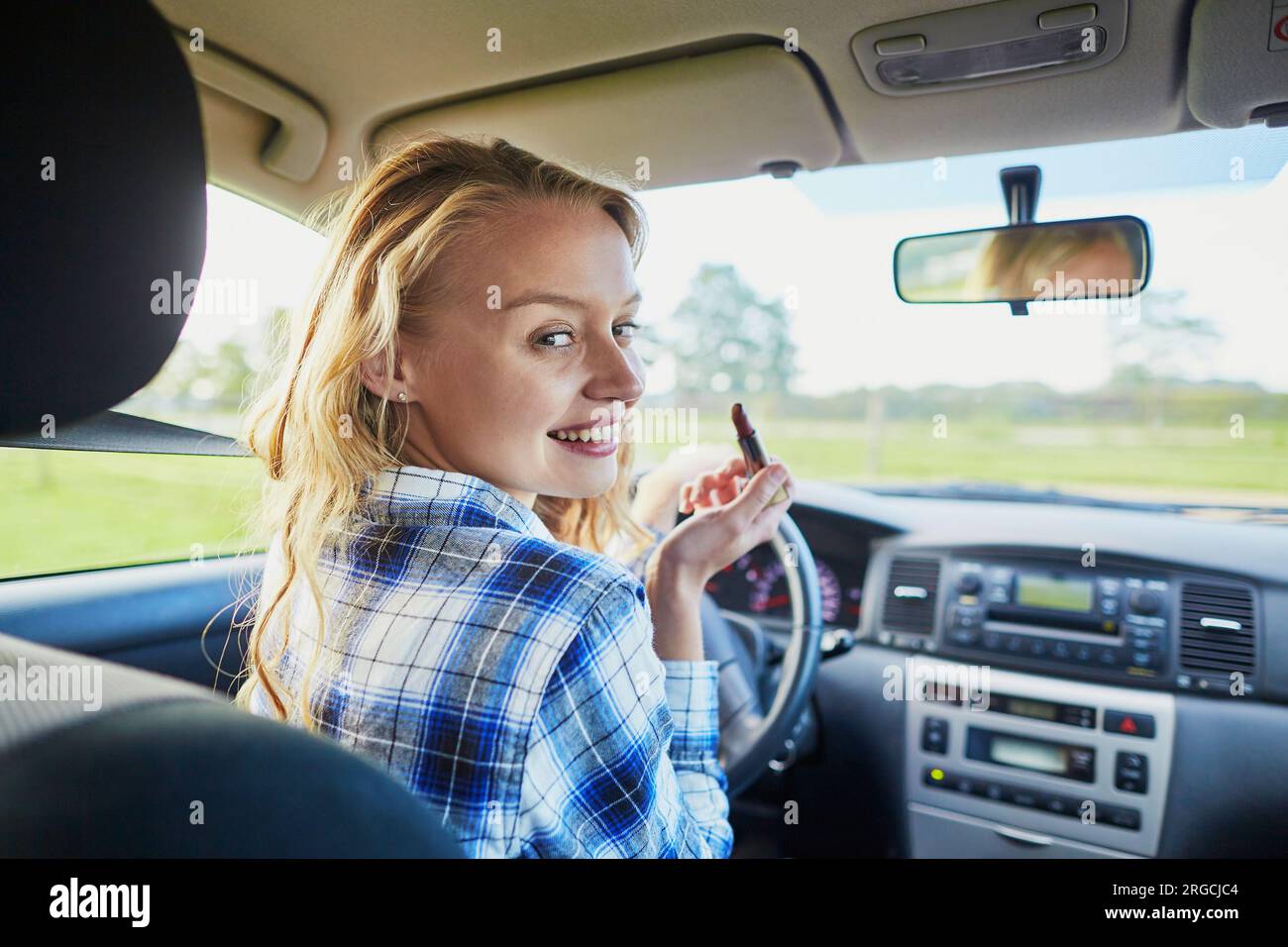 Beautiful blond woman applying lipstick in a car while driving Stock ...