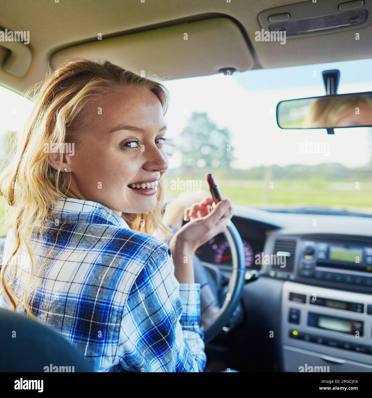 Beautiful blond woman applying lipstick in a car while driving Stock ...