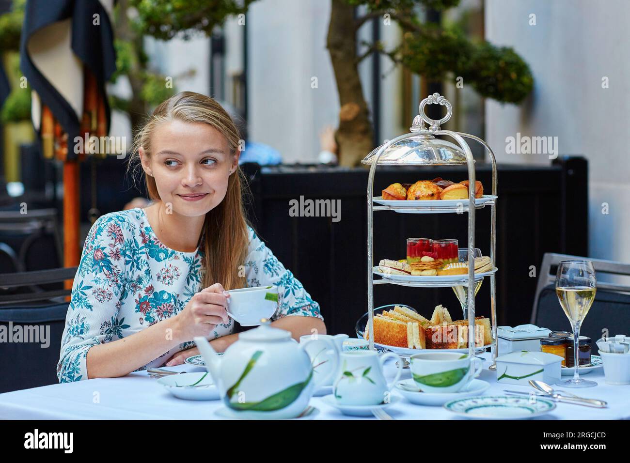 Beautiful young woman enjoying afternoon tea with selection of fancy ...