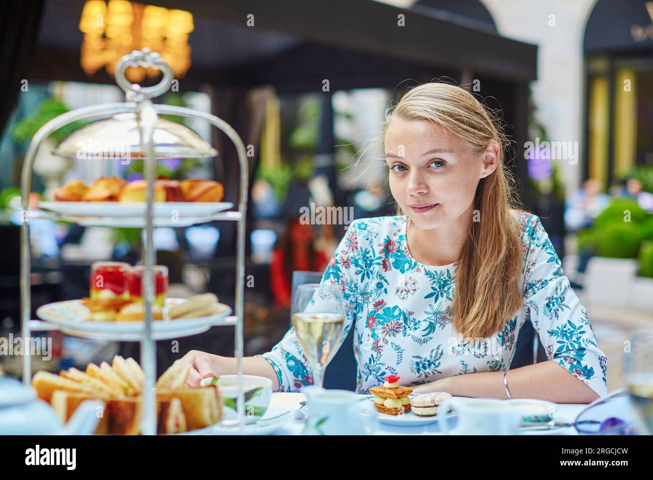 Beautiful young woman enjoying afternoon tea with selection of fancy ...
