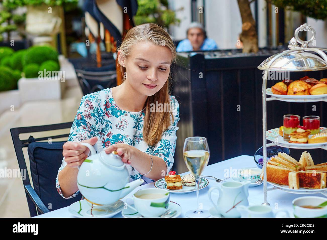 Beautiful young woman enjoying afternoon tea with selection of fancy ...