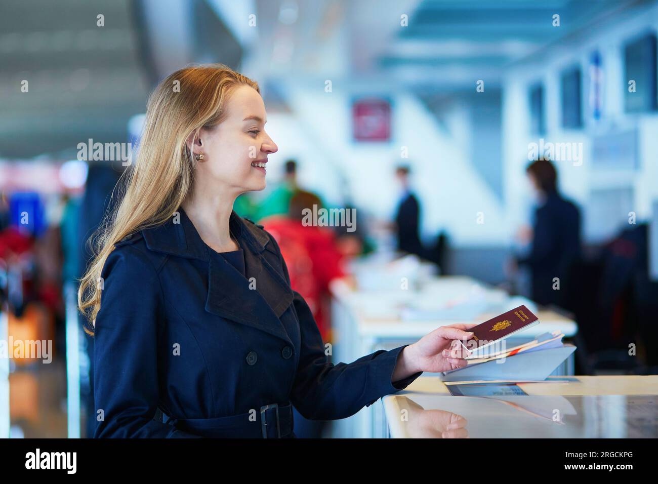 Young woman in international airport at check-in counter, giving her ...