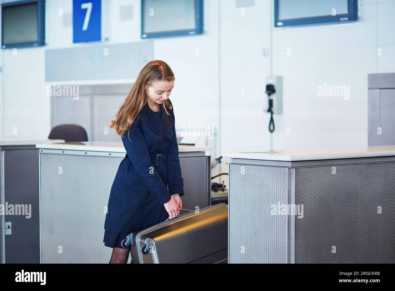 Young woman in international airport at check-in counter, putting her ...