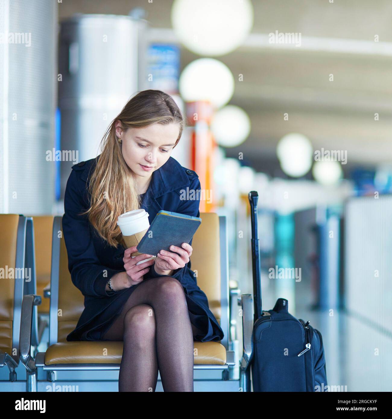 Young woman in international airport reading a book while waiting for ...