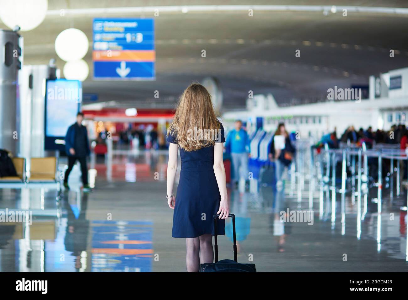 Young woman in international airport, walking with her luggage, back ...