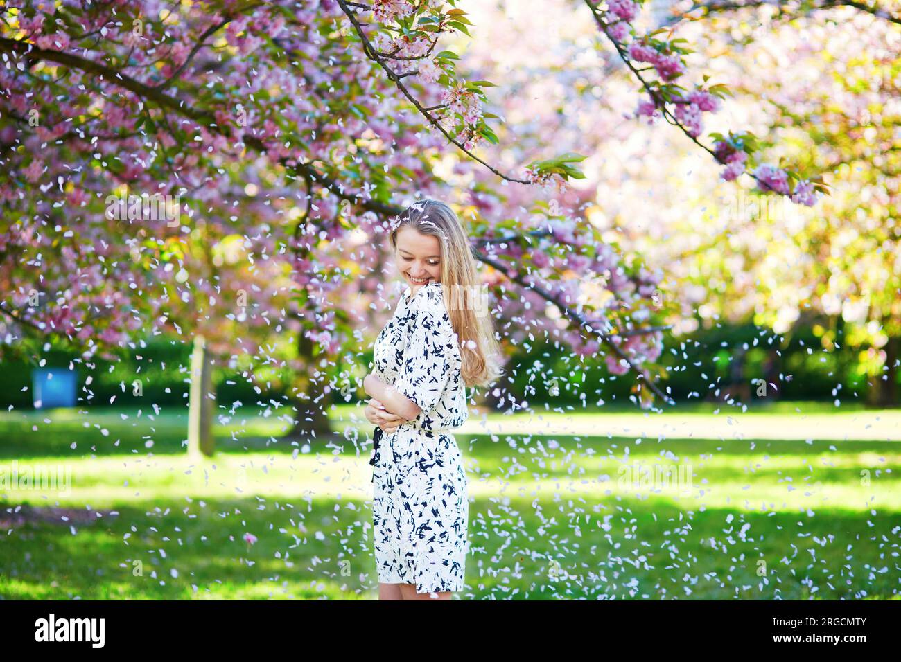 Beautiful young woman enjoying sunny day in park during cherry blossom ...