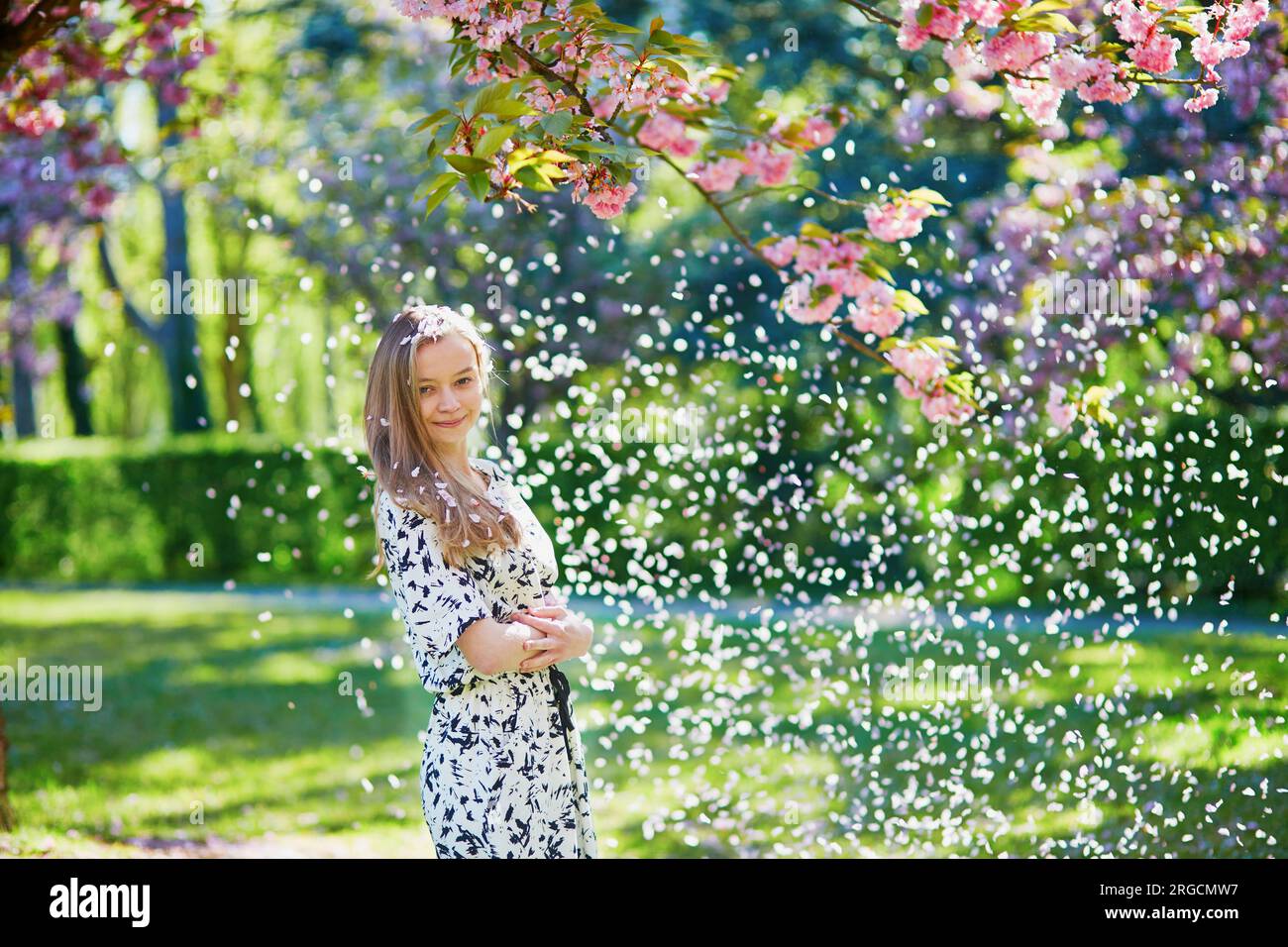Beautiful young woman enjoying sunny day in park during cherry blossom ...