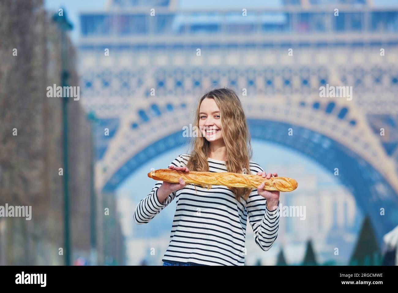 Beautiful young girl with fresh tasty traditional French bread ...