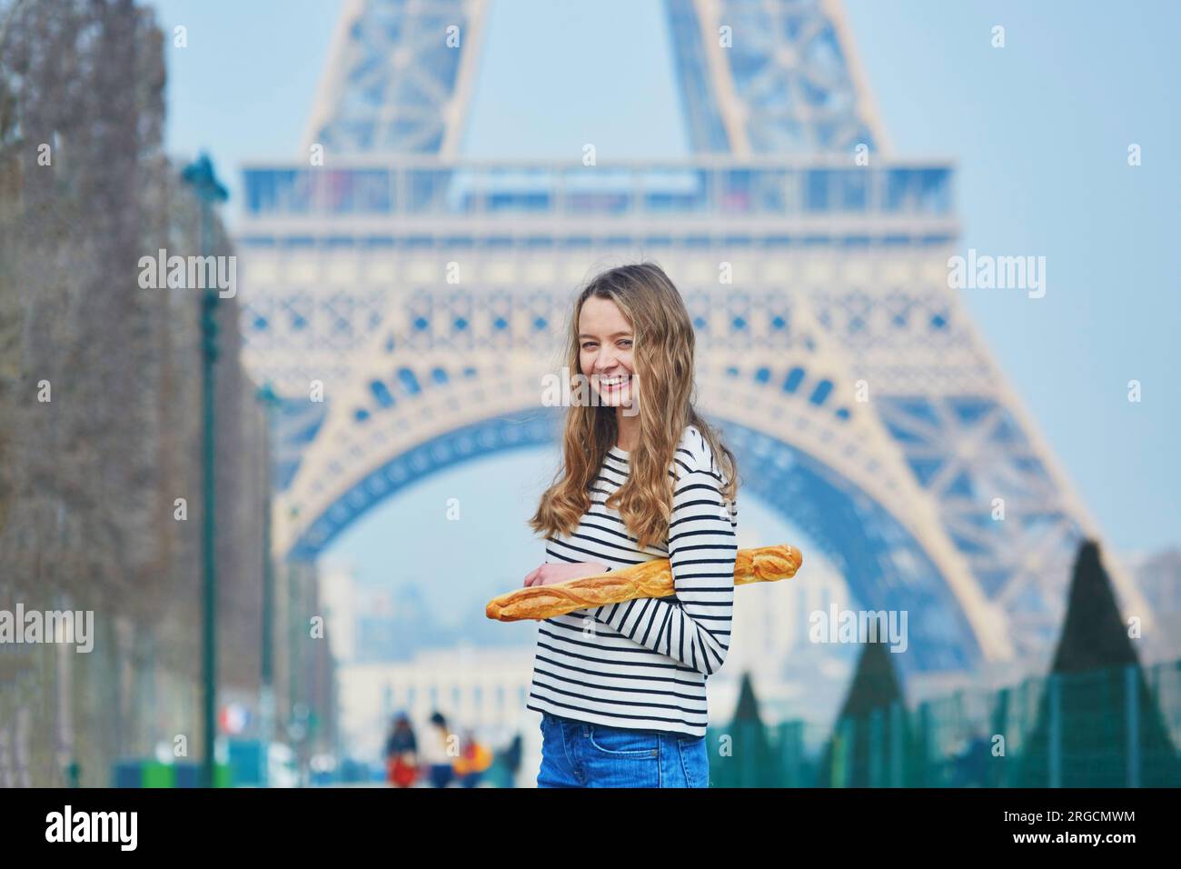 Beautiful young girl with fresh tasty traditional French bread ...