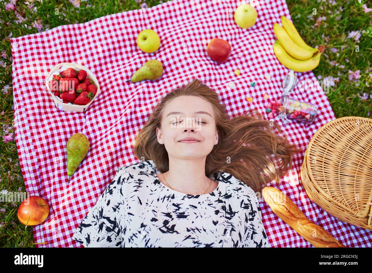 Beautiful young woman having picnic in parc, lying on her back with ...