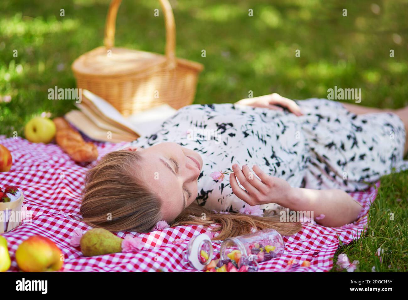 Beautiful young woman having picnic in parc, lying on her back with ...
