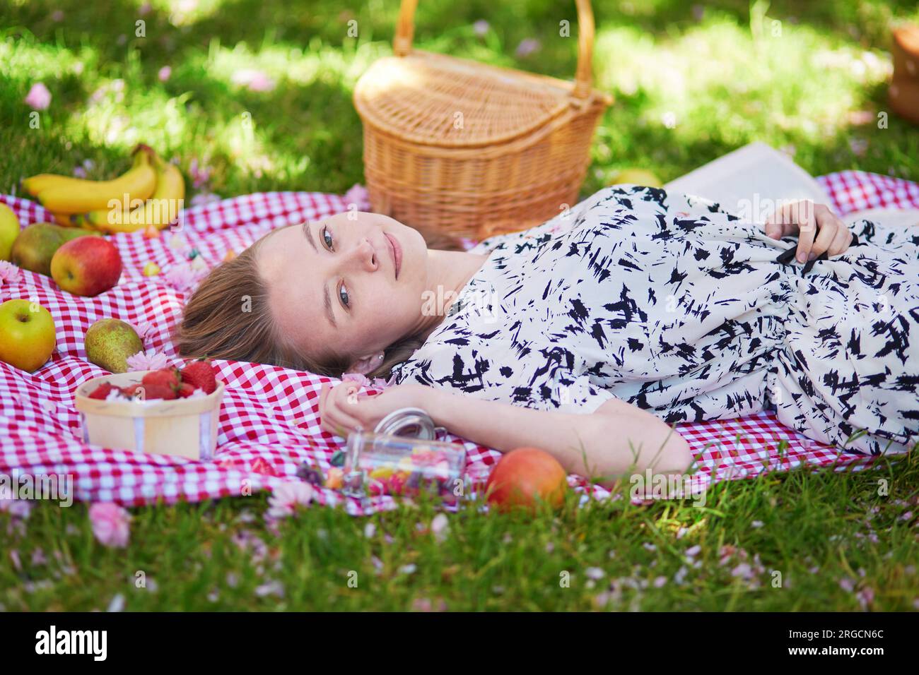Beautiful young woman having picnic in parc, lying on her back with ...