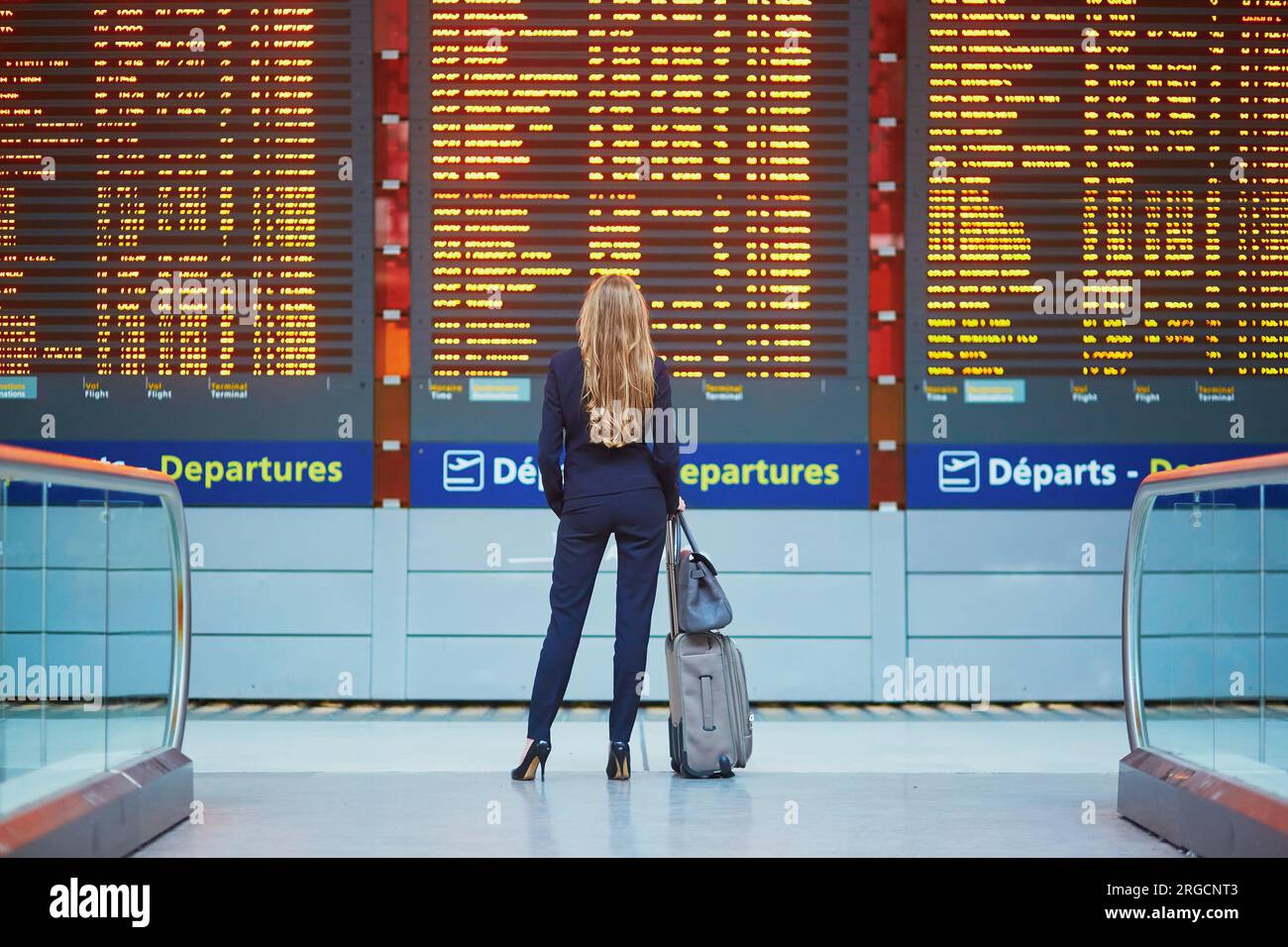 Young elegant business woman with hand luggage in international airport ...