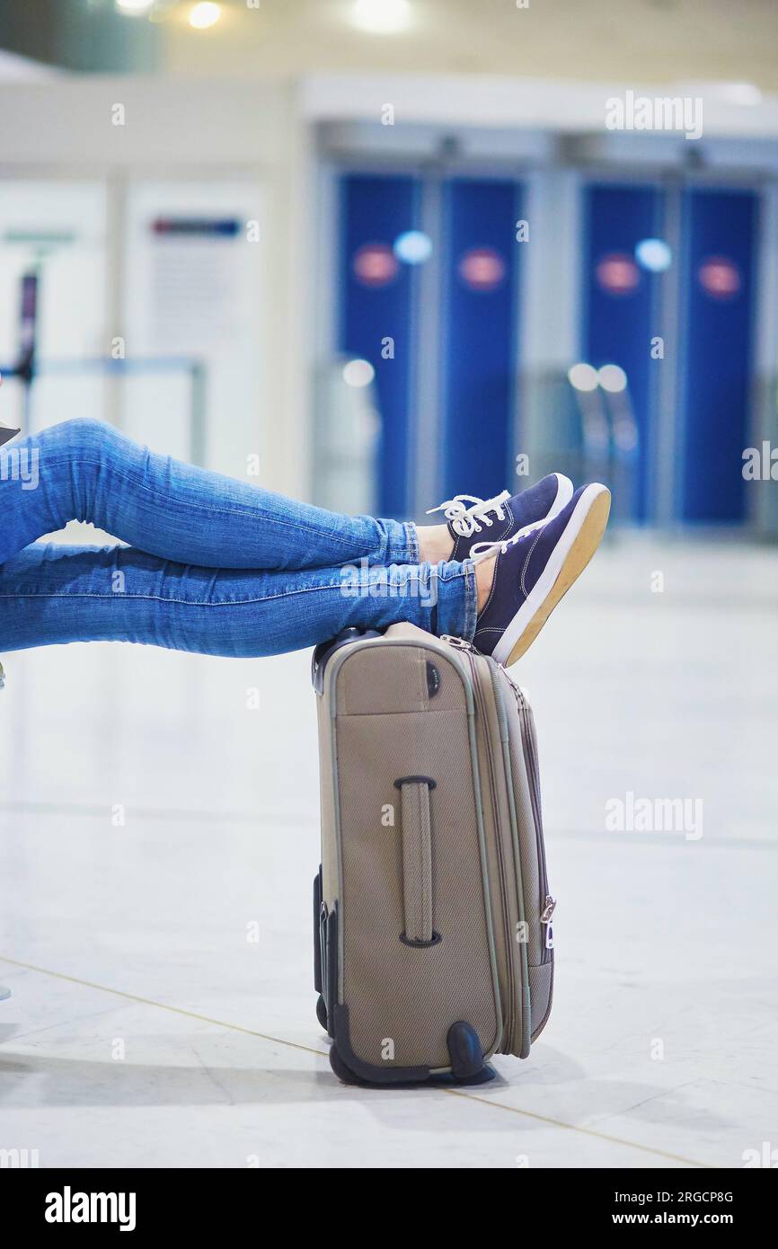 Closeup of woman feet on a suitcase in international airport. Delayed ...