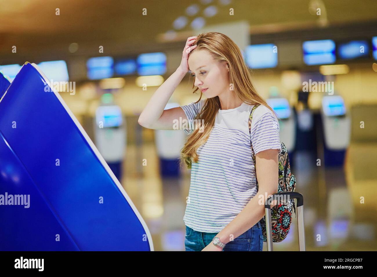 Young tourist girl with backpack and carry on luggage in international ...