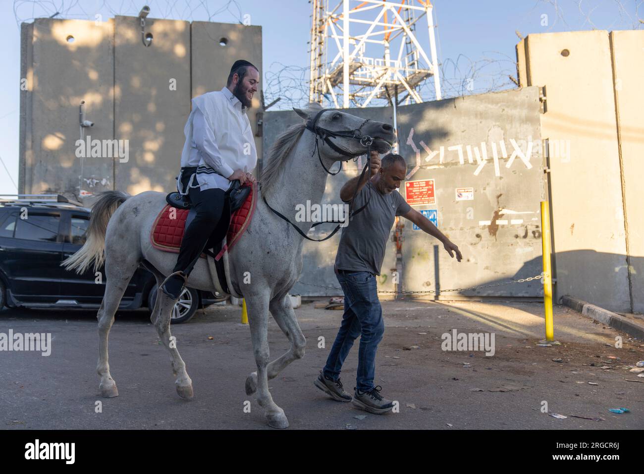 An ultra-Orthodox Jewish man rides a horse led by a Palestinian at the ...