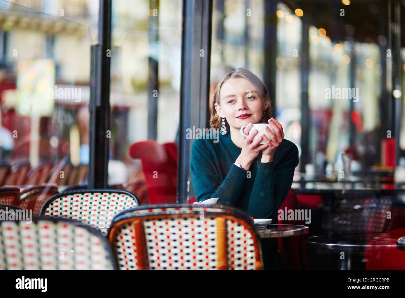 Elegant French woman drinking coffee in Parisian cafe near the window ...