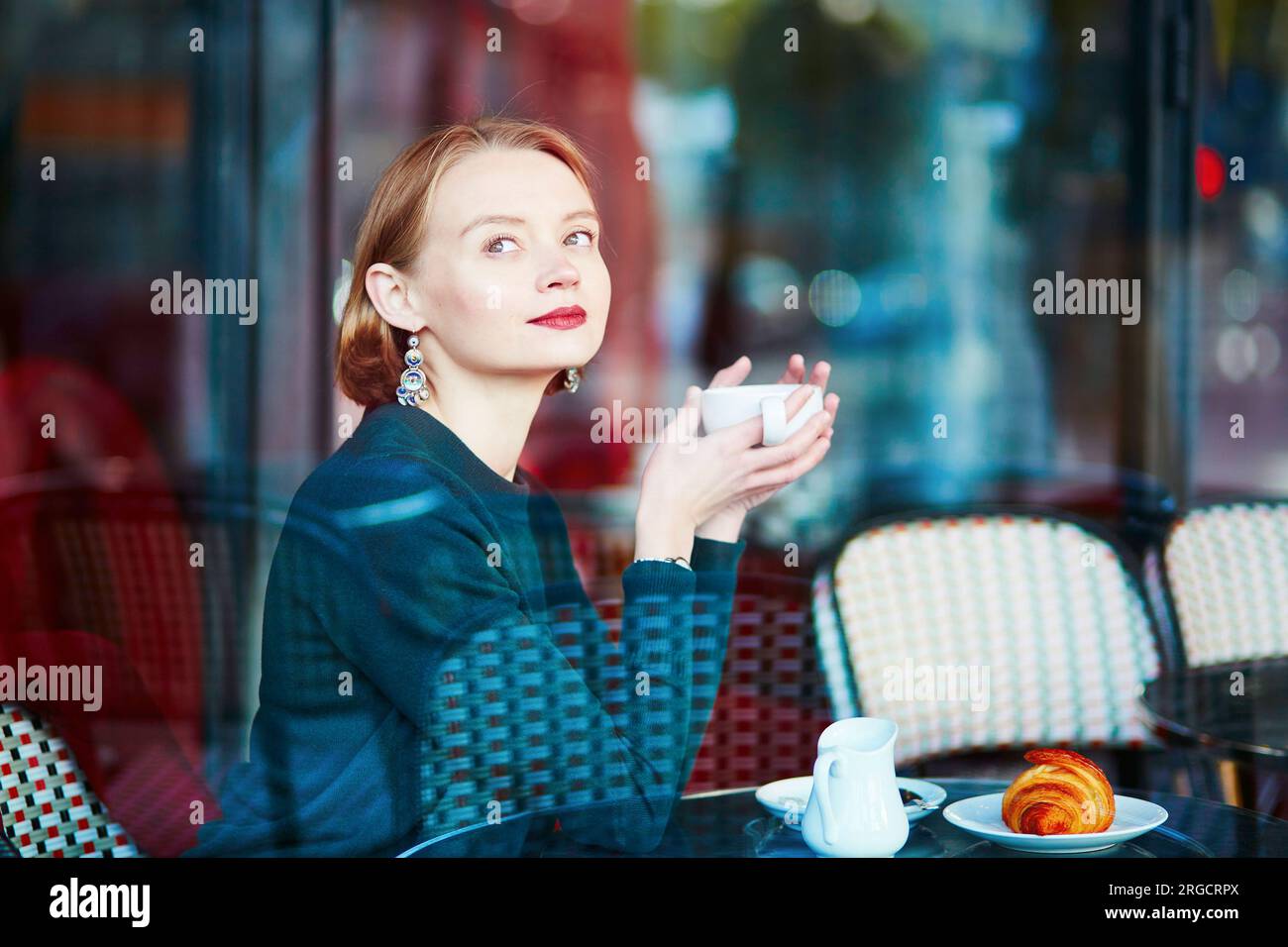 Elegant French woman drinking coffee in Parisian cafe near the window ...