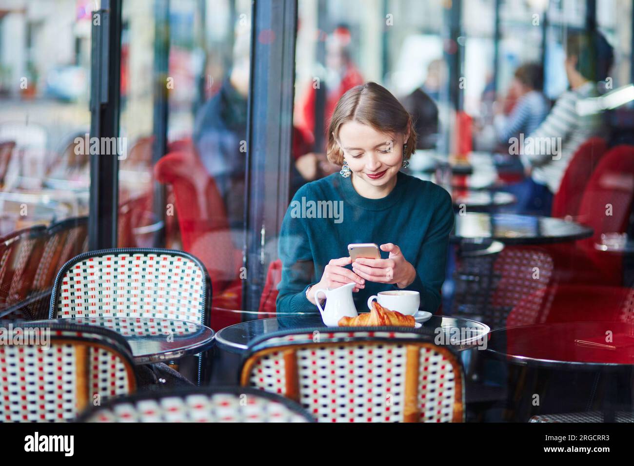 Elegant French woman drinking coffee in Parisian cafe near the window ...