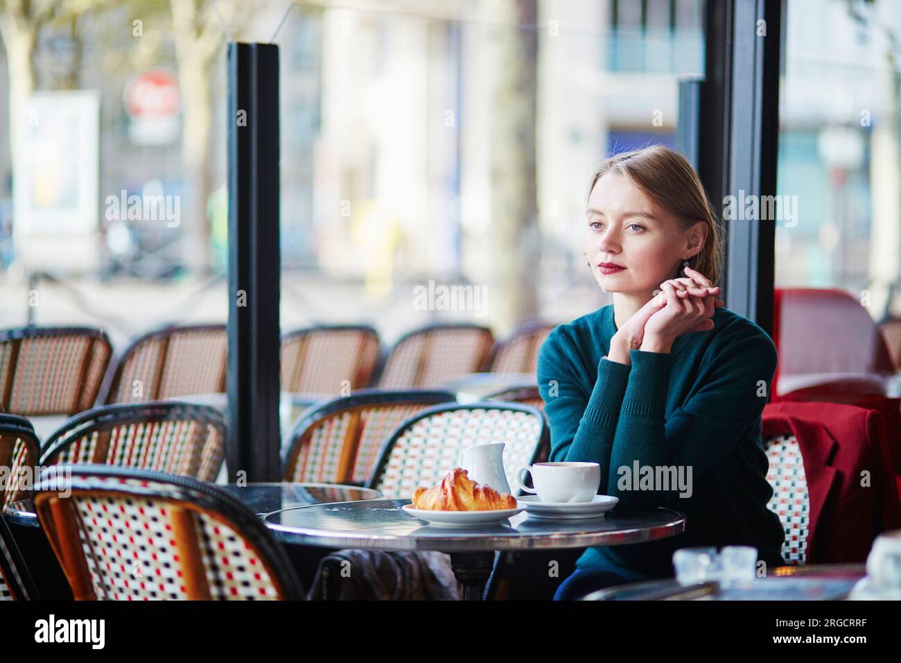 Elegant French woman drinking coffee in Parisian cafe near the window ...