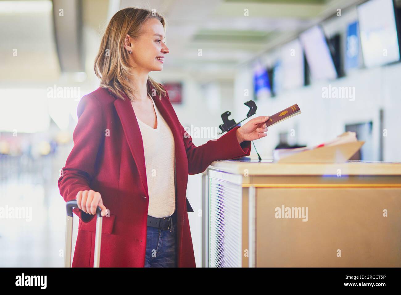 Young woman in international airport at check-in counter giving her ...
