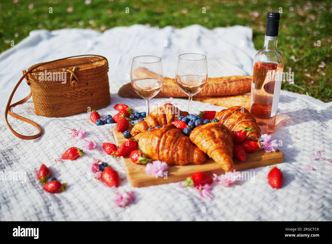Beautiful picnic with rose wine, French croissants and fresh berries ...