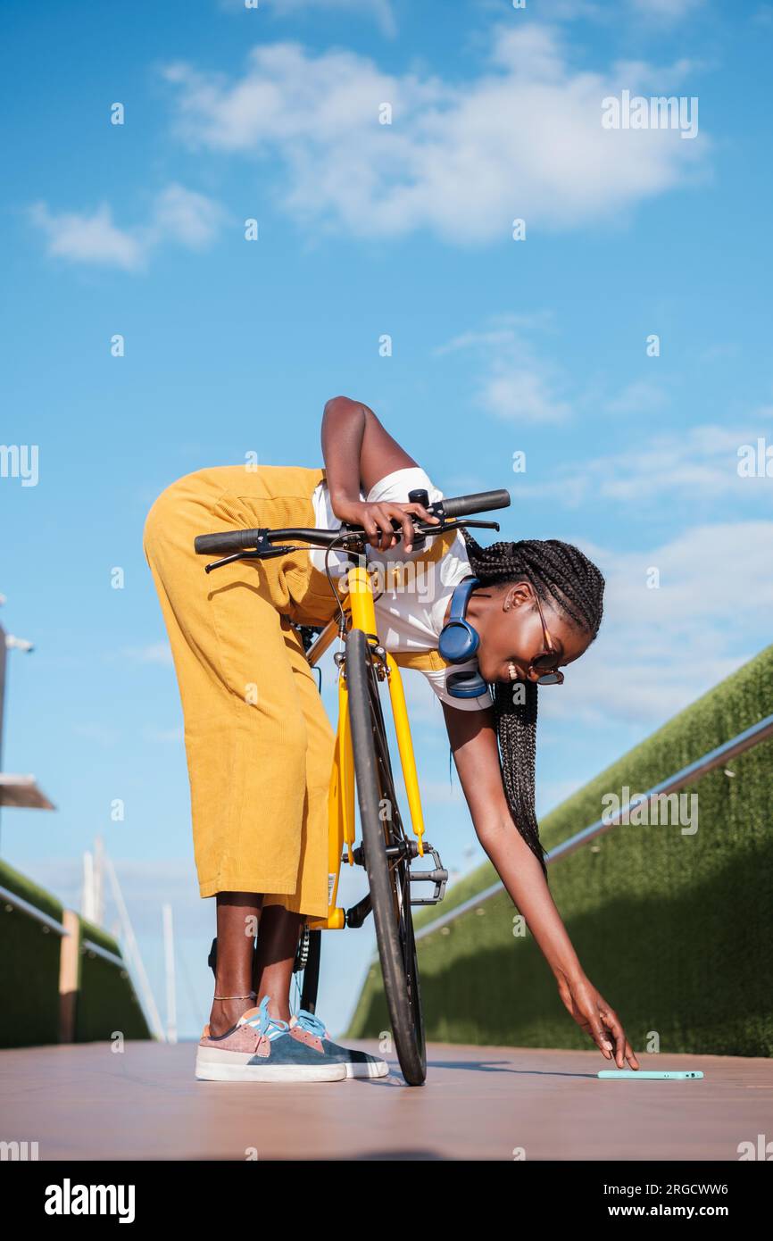 Young woman picking up her smartphone from the ground after it fell out ...
