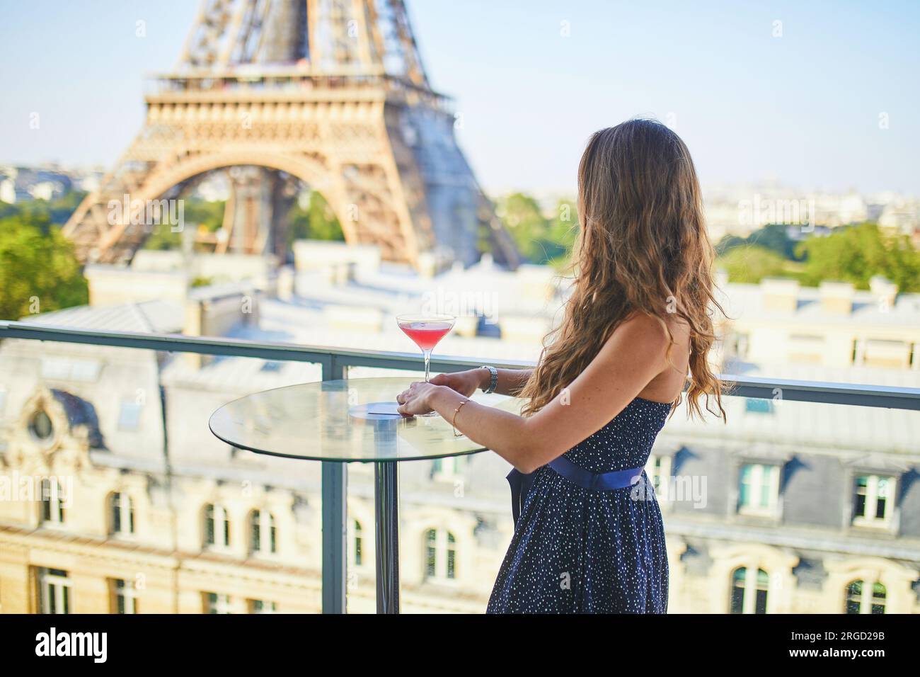 Beautiful young woman drinking alcoholic cocktail in a rooftop ...