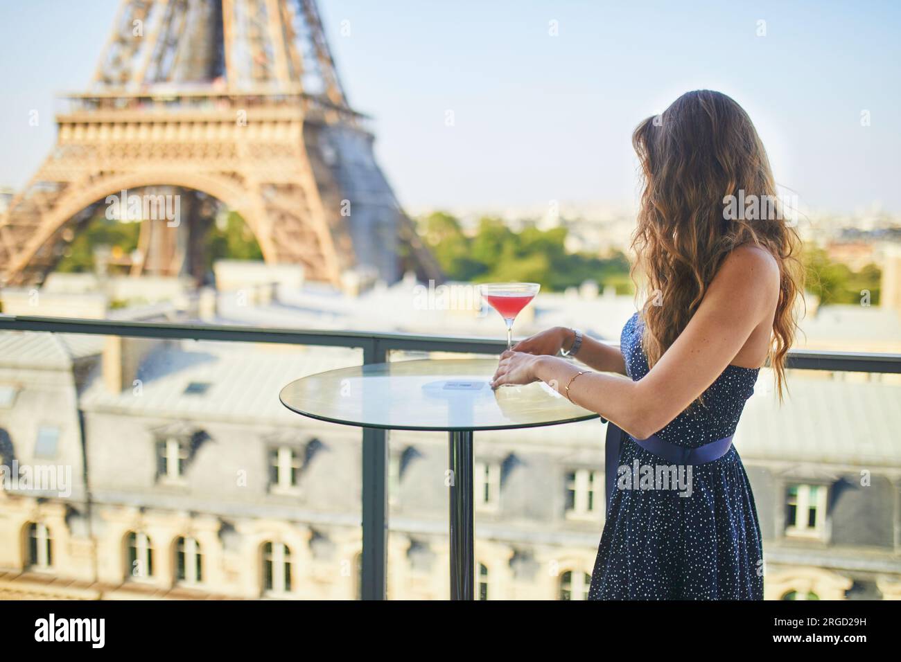 Beautiful young woman drinking alcoholic cocktail in a rooftop ...