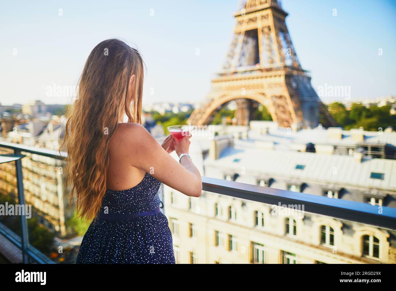 Beautiful young woman drinking alcoholic cocktail in a rooftop ...